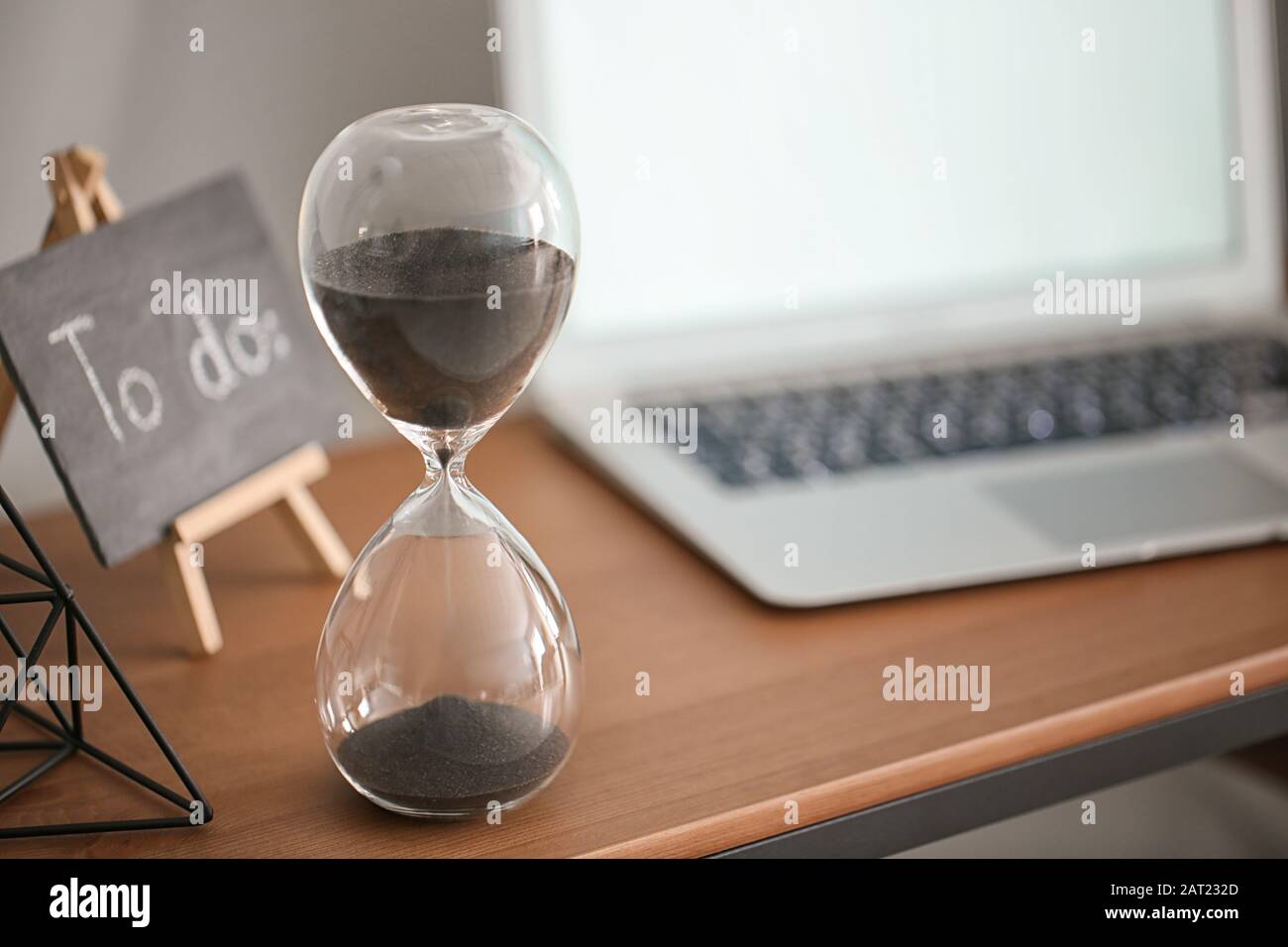 Hourglass with laptop on table in office. Time management concept Stock ...