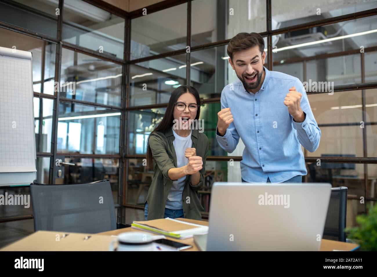 Tall young man and his female colleague feeling successful in the ...