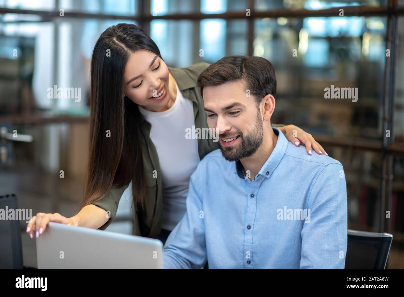 Long-haired asian cute girl touching her partners shoulder and smiling ...