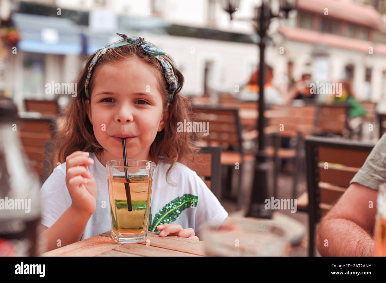 Happy little girl in a cafe on the street pb cocktail. Walking and ...