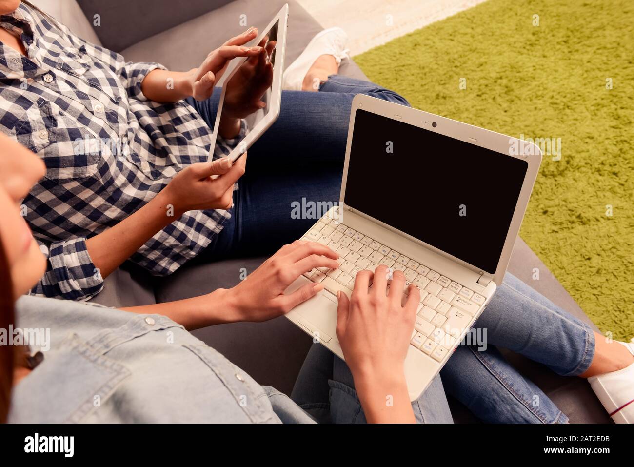 Two young students doing task and working on laptop and digital tablet ...