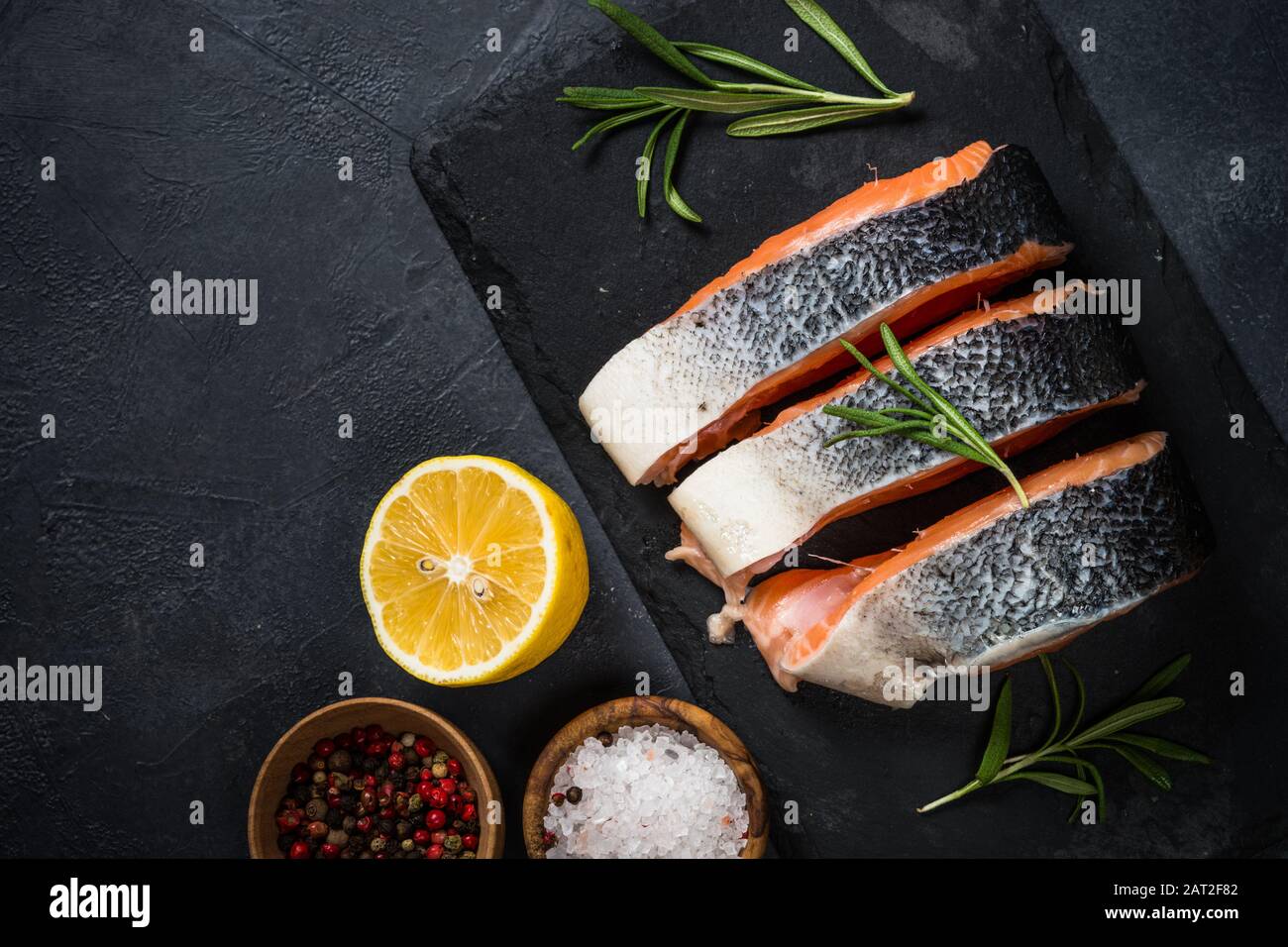 Raw salmon steak on black top view Stock Photo - Alamy