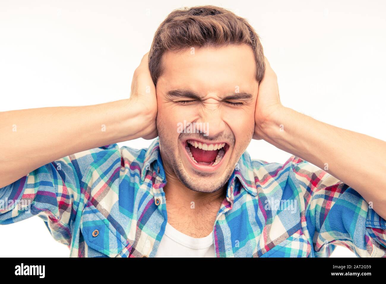 Young man covering his ears and shouting Stock Photo - Alamy
