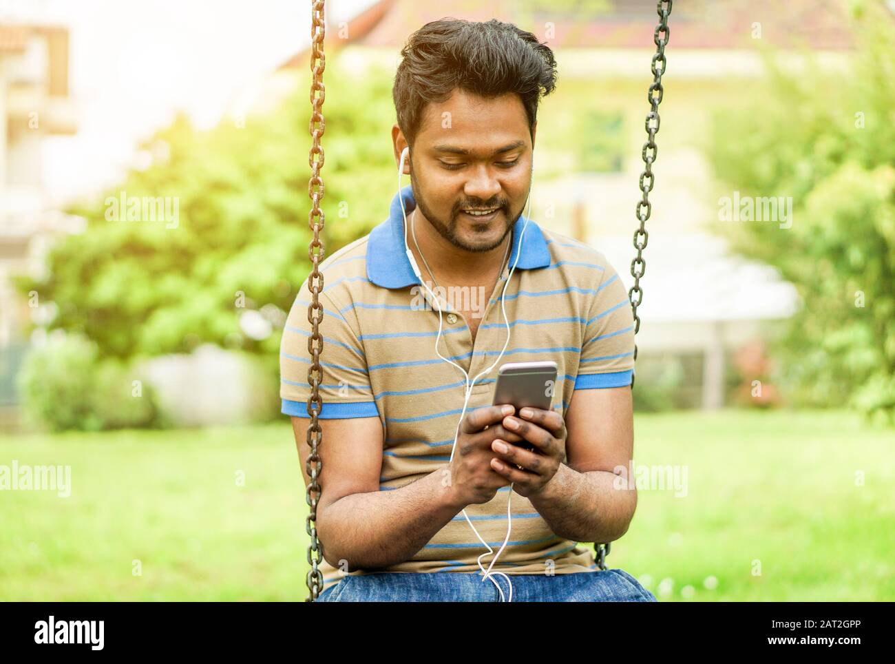 Happy young Indian man watching videos and sharing with mobile cell ...