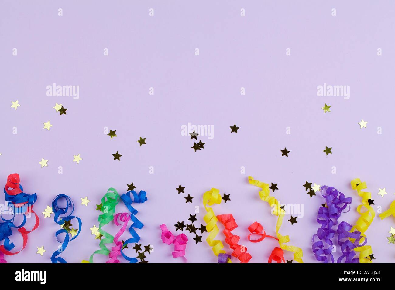 Festive party border or frame of colorful spiral streamers and confetti on pink background, copy ...