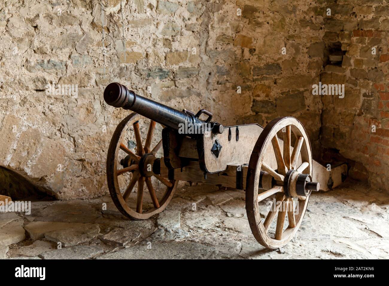 An old weapon with wooden wheels on the background of a brick wall of a ...
