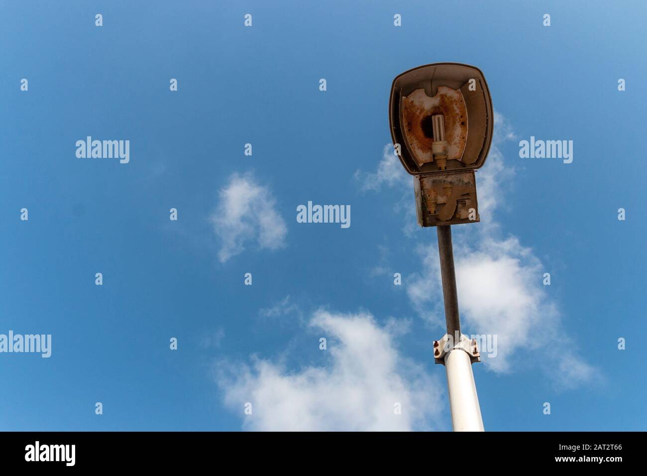 A close up view of a old broken outdoor street light with the big blue ...