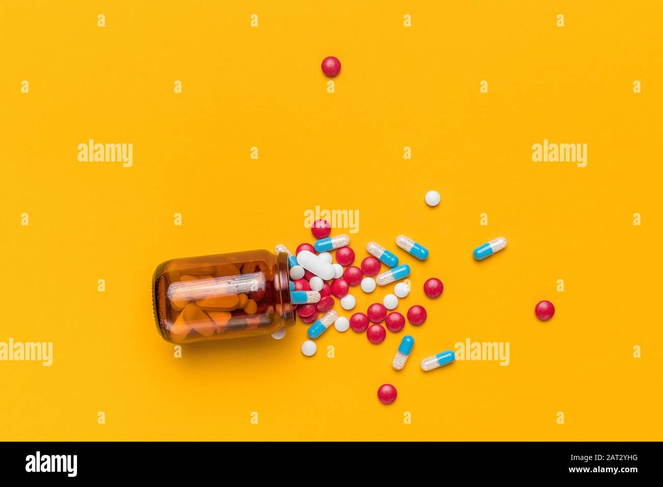 Film coated pills and capsules spilled from bottle with copy space, top ...