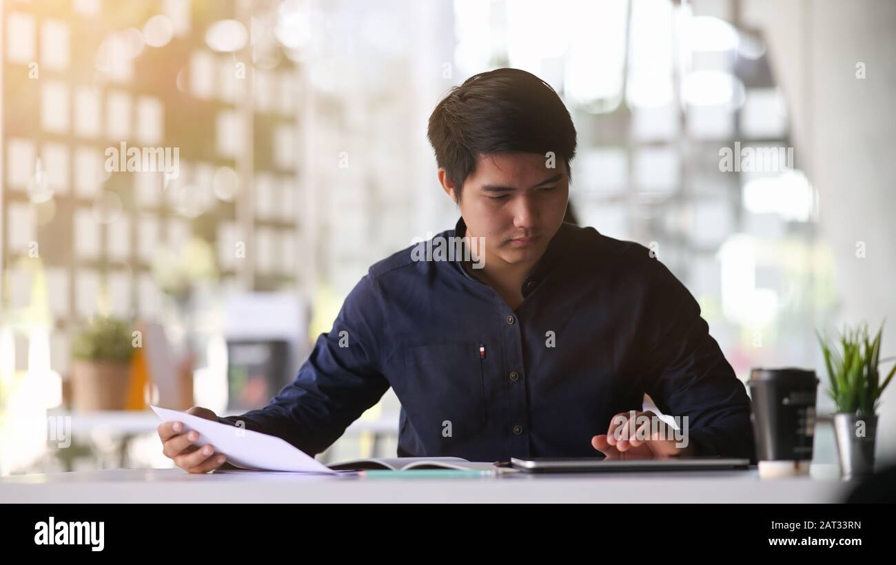 Young smart office worker concentrating on his work and using a ...