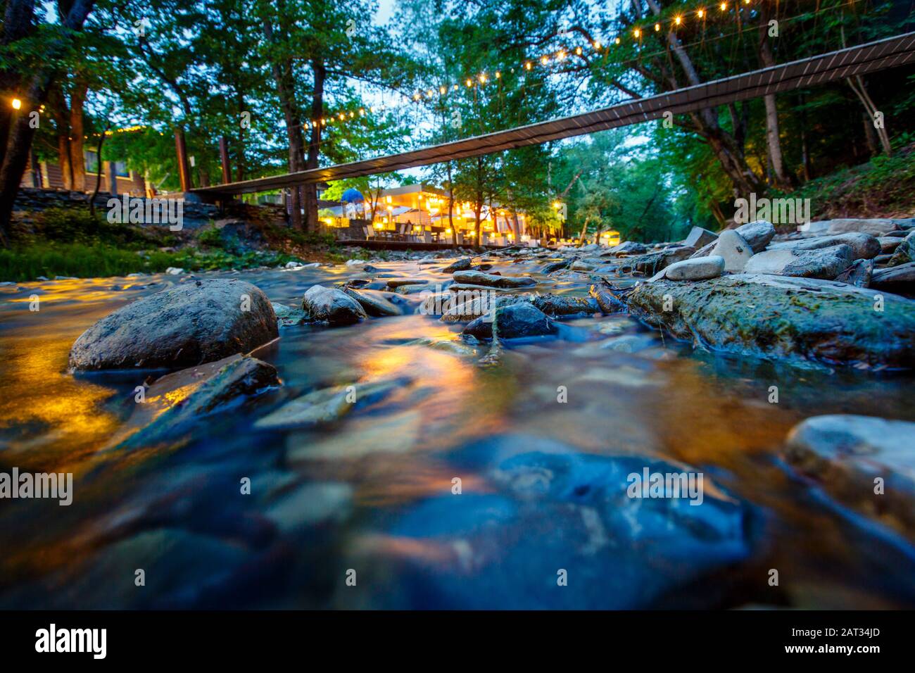 a small pedestrian suspension bridge over a shallow mountain river ...