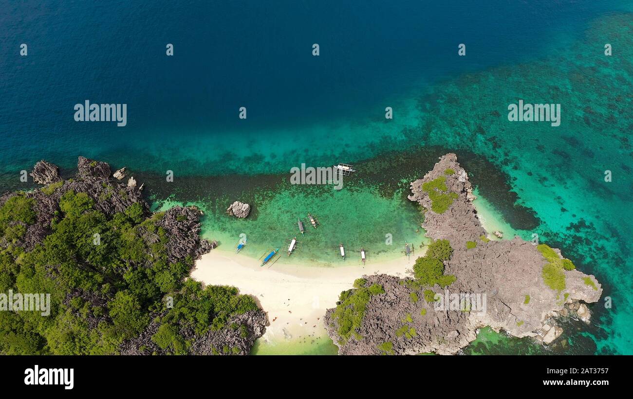 Sandy beach with tourists and tropical island by atoll with coral reef ...