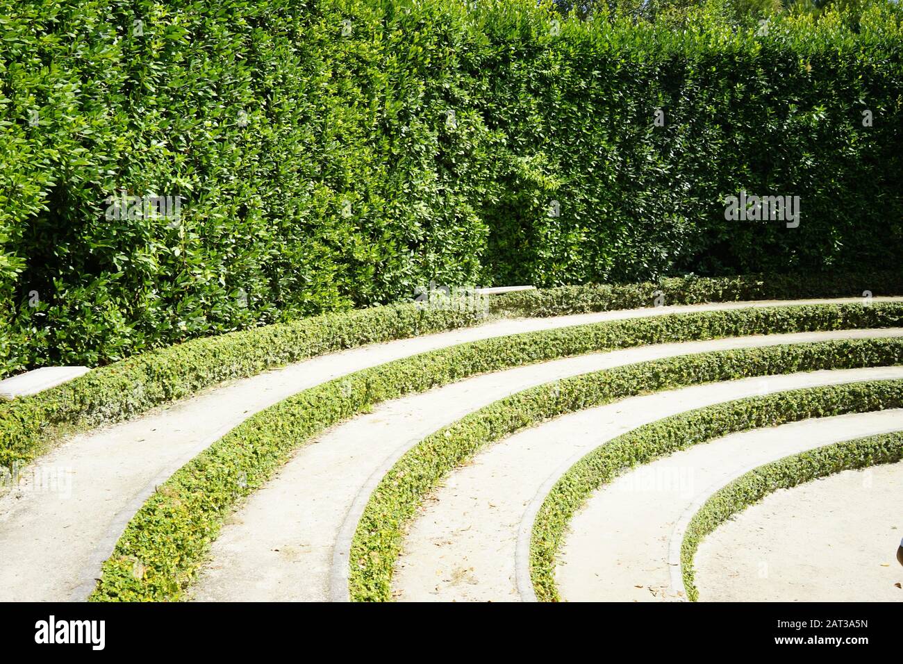 Wide shot of a park with circular pathways and a hedge surrounding it ...