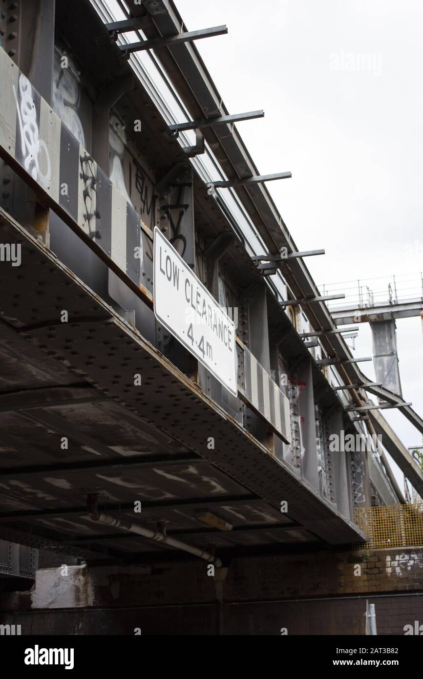 Angled shot of a sign on the side of an overpass indicating a low ...