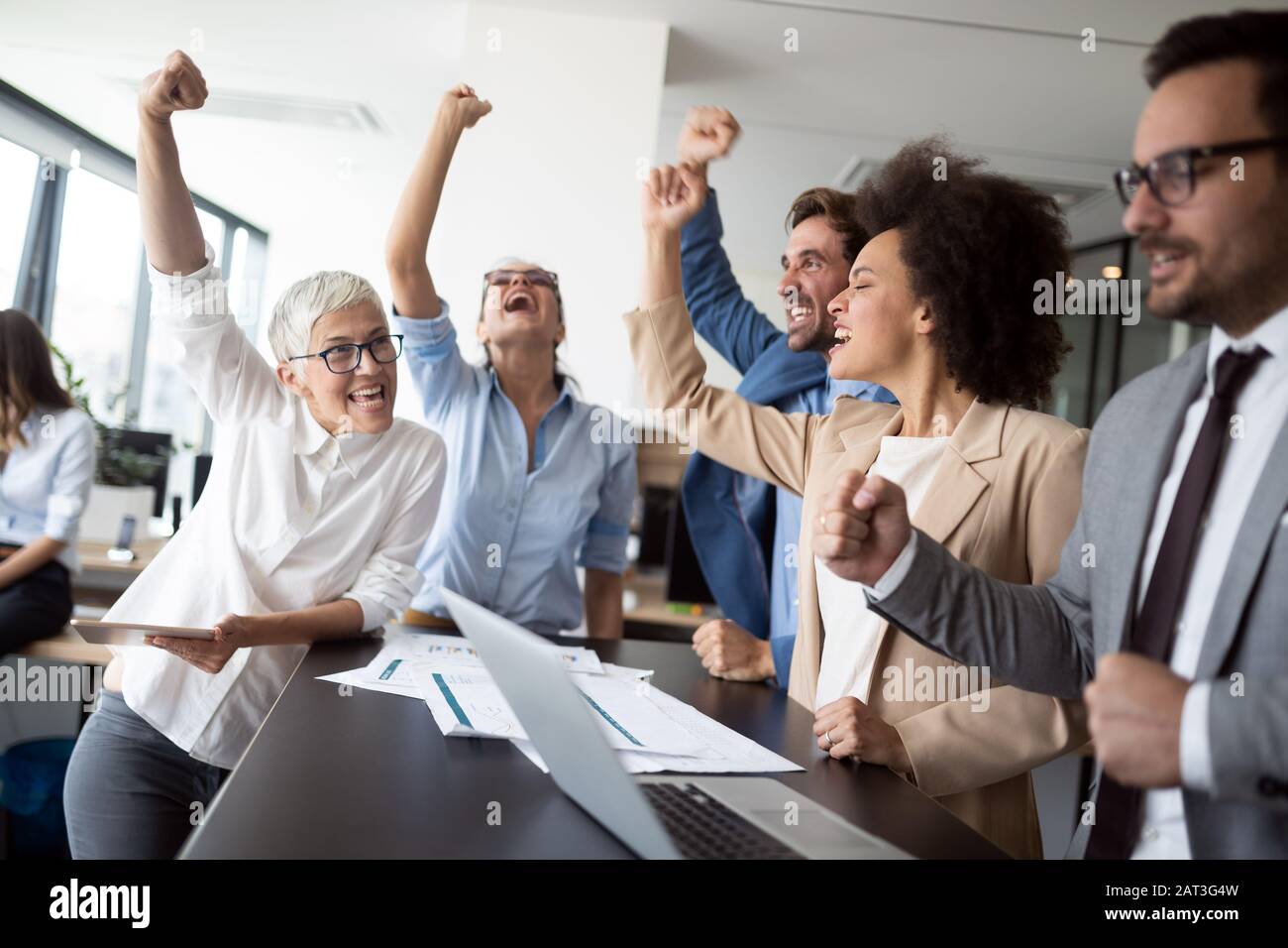 Happy business people celebrating success at company Stock Photo - Alamy