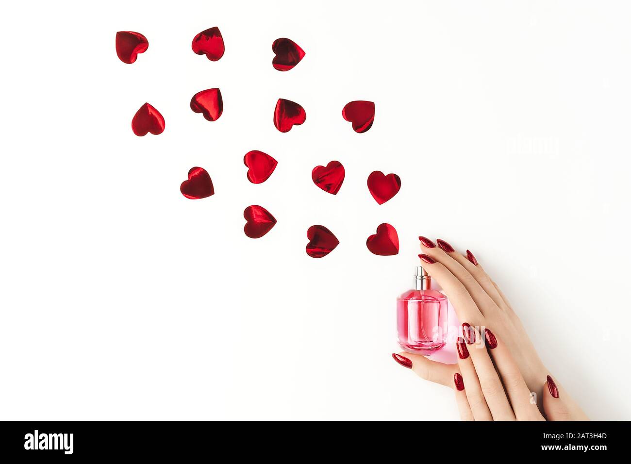 Beautiful female hands with trendy red manicure holding stylish bottle ...