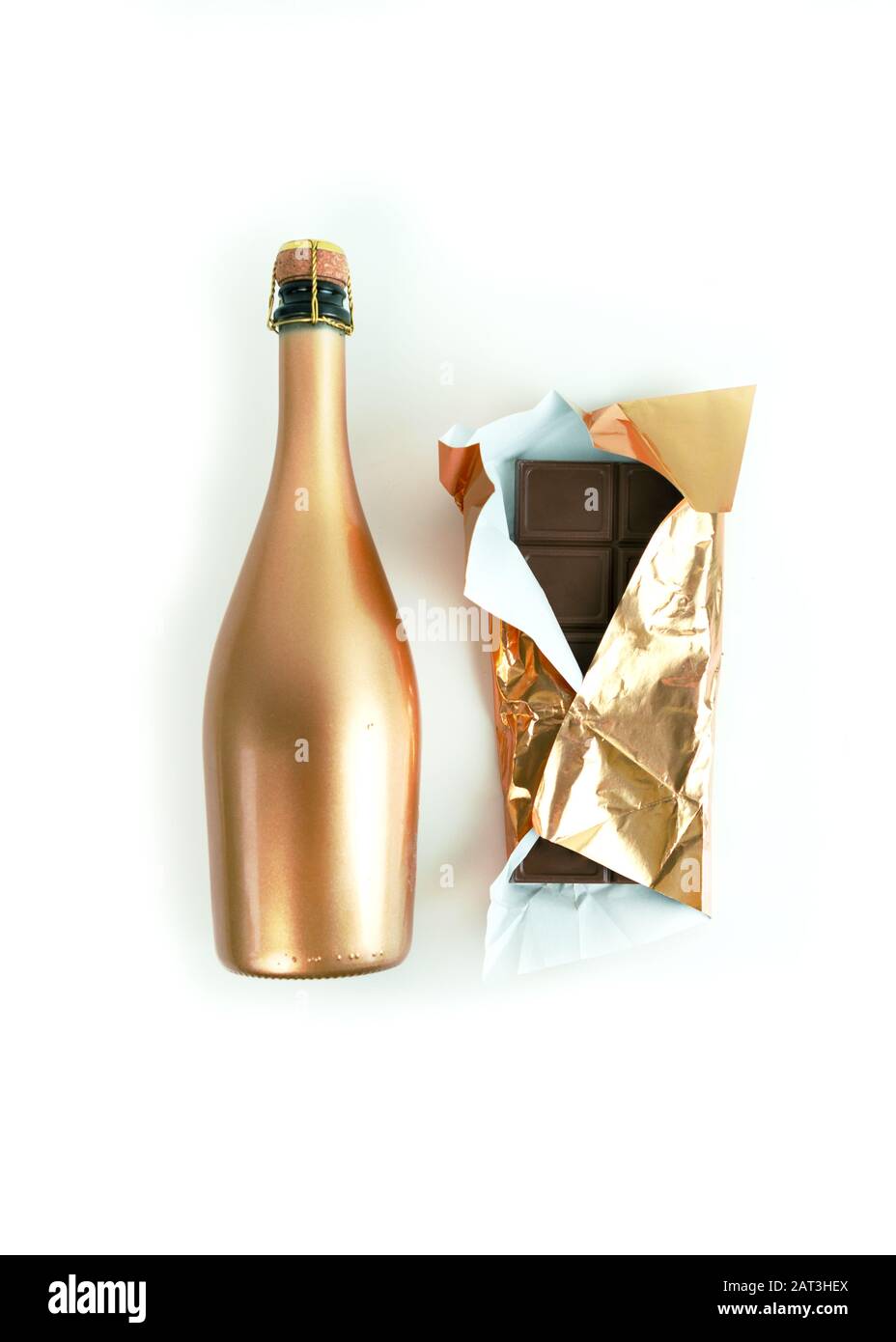 Golden champagne bottle and chocolate bar in gold wrapper on a white ...