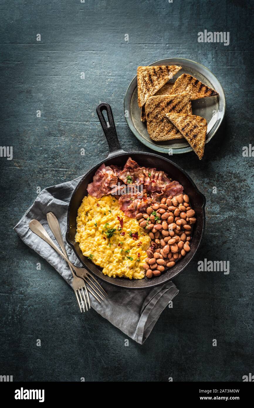 English breakfast scrambled eggs grilled bacon beans and toast bread ...