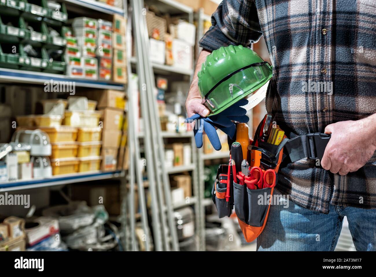 Electrician in the electrical component store he is holding his helmet ...