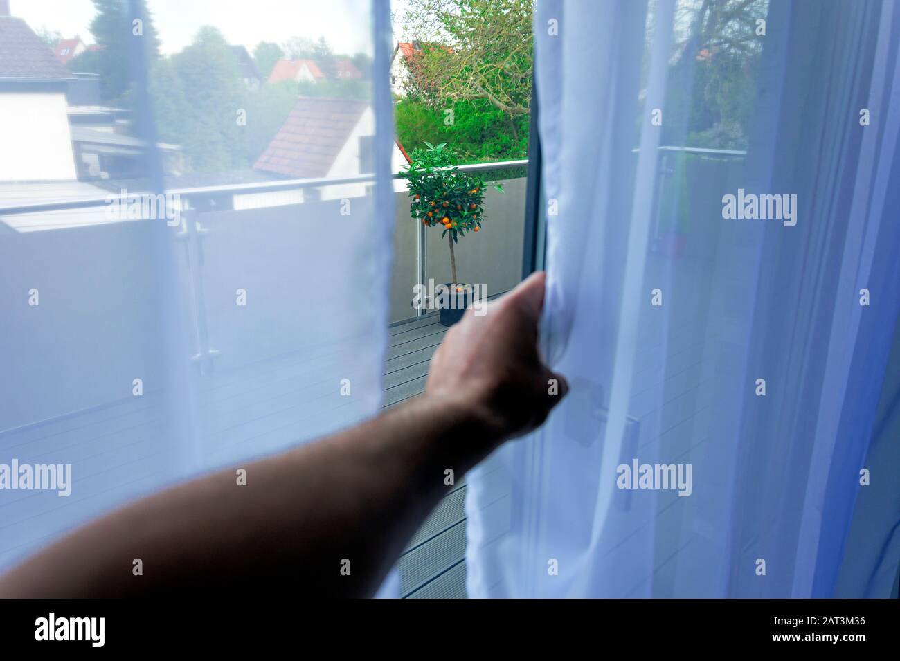 Male hand pushing curtains to the side in front of the window and ...