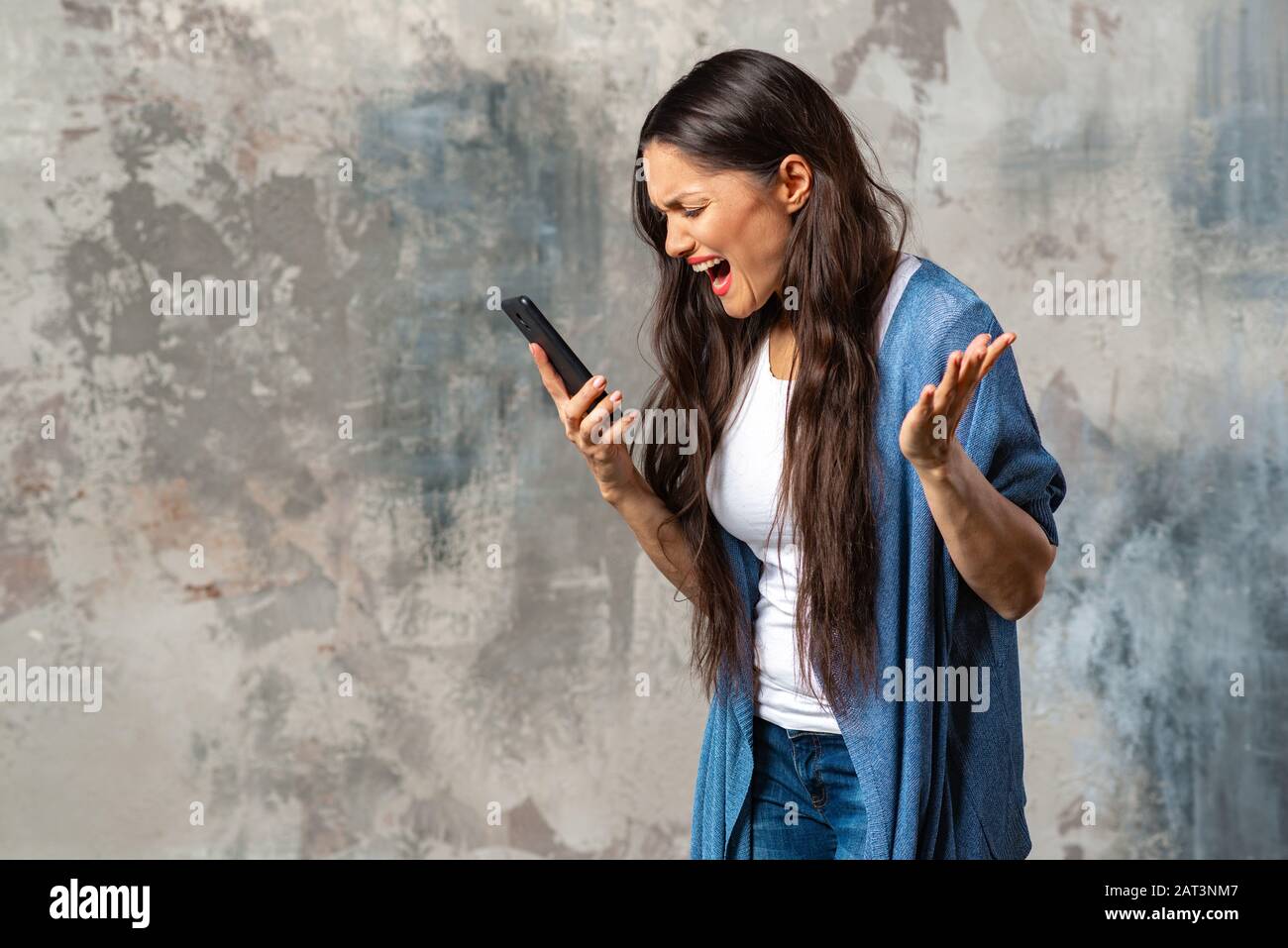 Angry woman looking at the screen of the smartphone and screaming ...