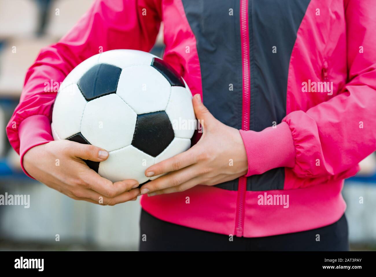 Adult's hands holding football ball. Man or woman wearing sportwear ...
