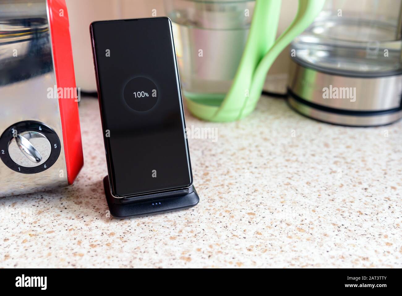 smartphone wireless charging on charging stand with 100 percent icon on ...