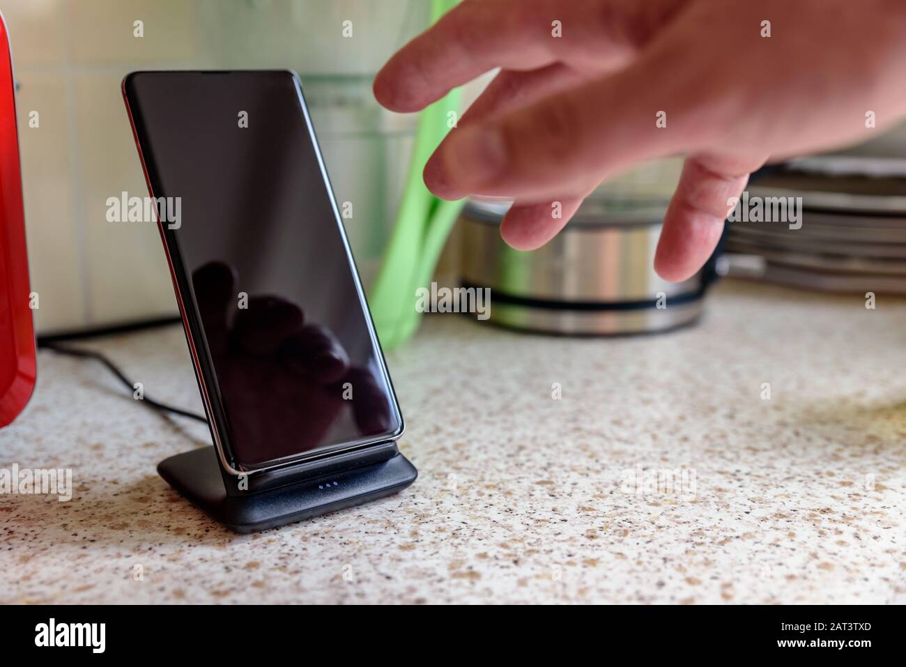 smartphone wireless charging on charging stand on kitchen tabletop ...
