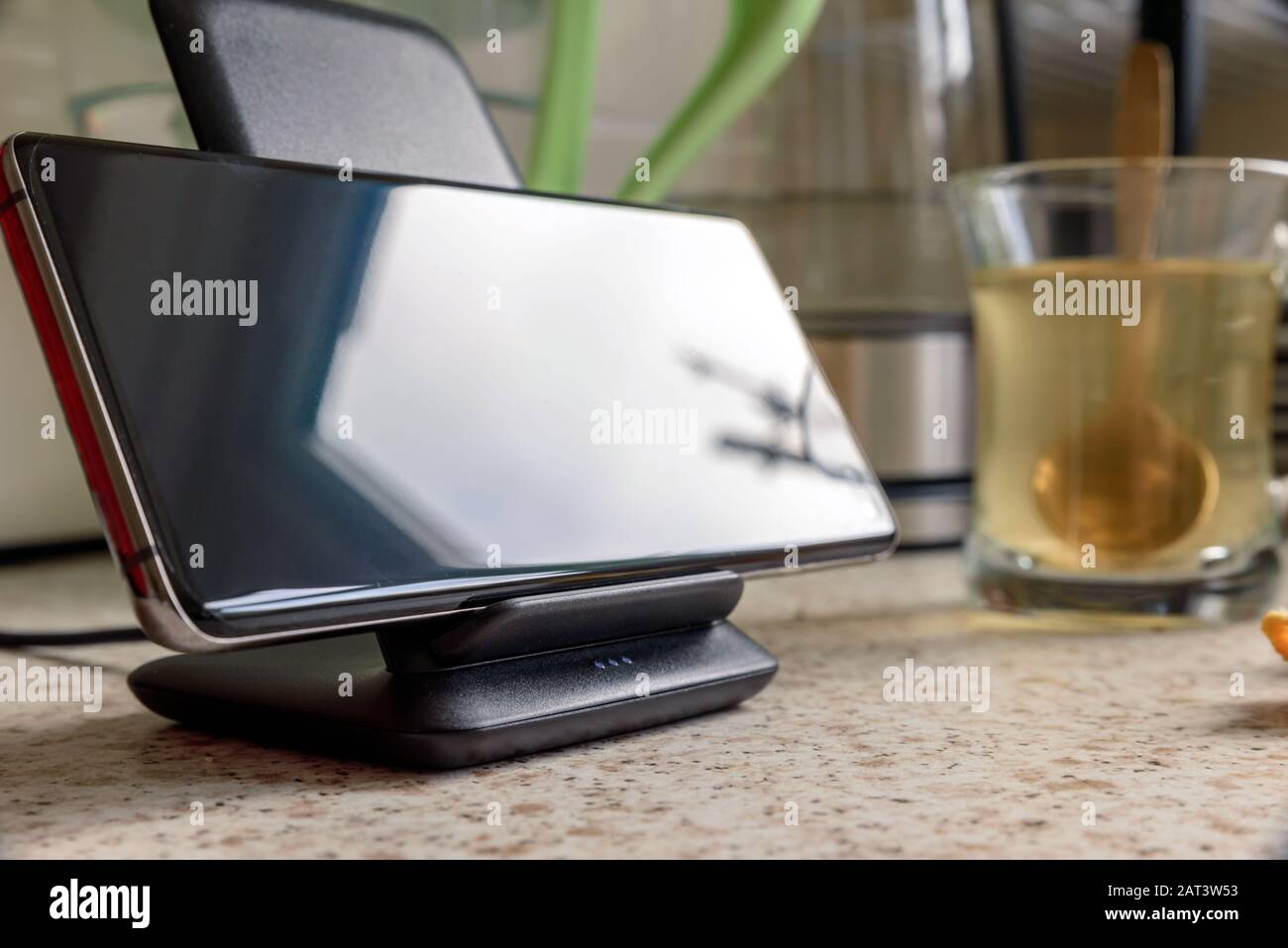 smartphone wireless charging on charging stand on kitchen tabletop ...