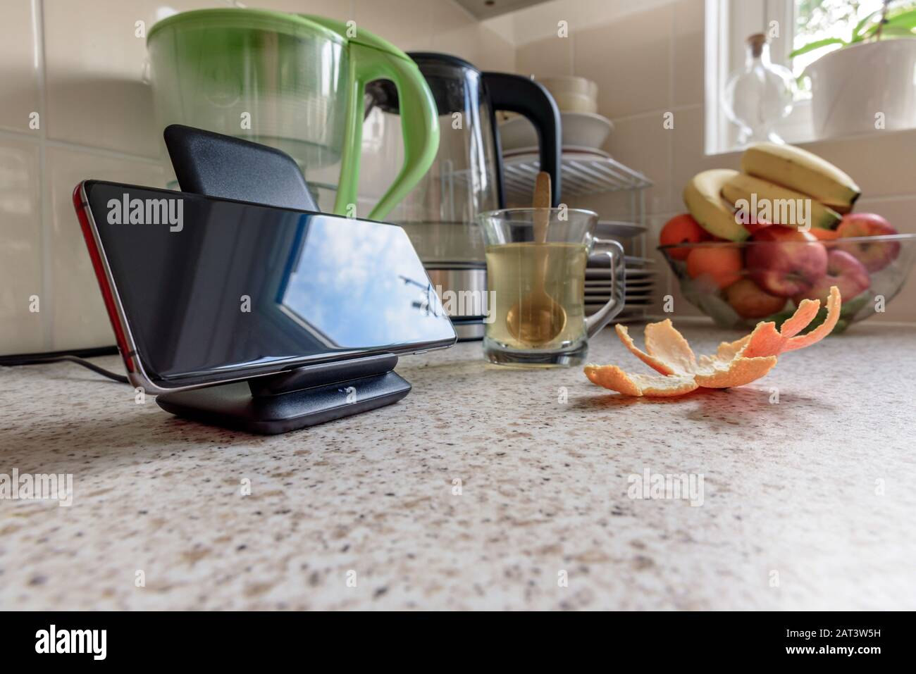 smartphone wireless charging on charging stand on kitchen tabletop ...