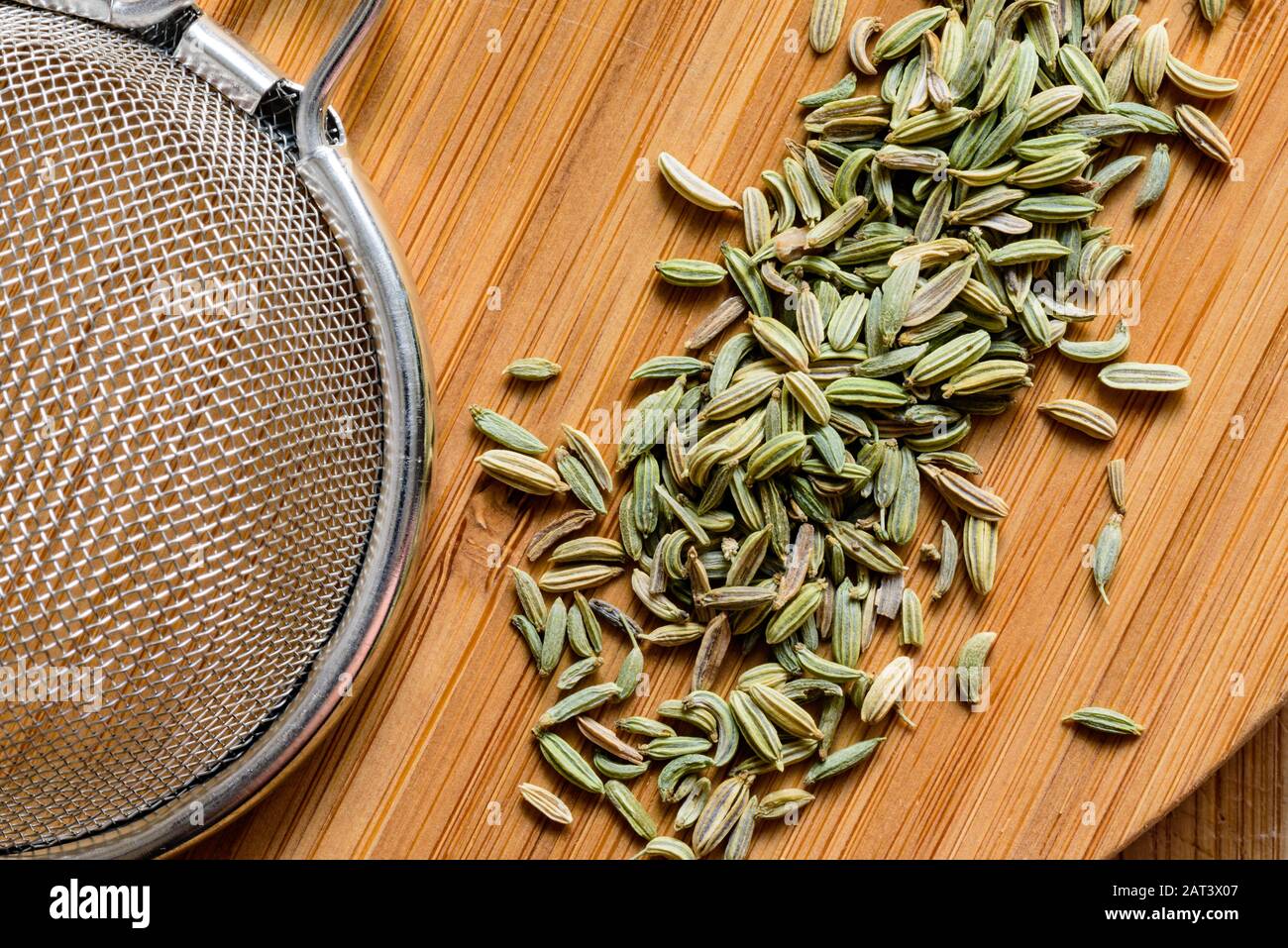 fennel seeds loose with sieve on wooden board ready to be brewed as tea ...
