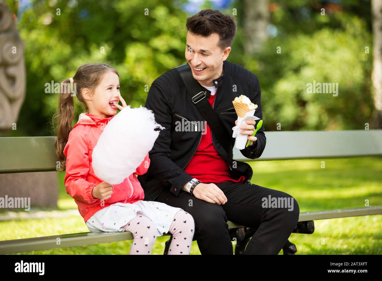 Cute girl and father eating cotton candy and ice cream, sitting on ...