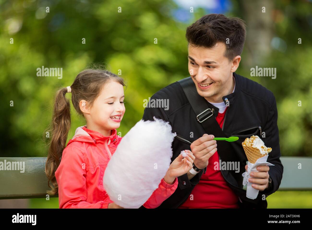 Cute girl and father eating cotton candy and ice cream, sitting on ...