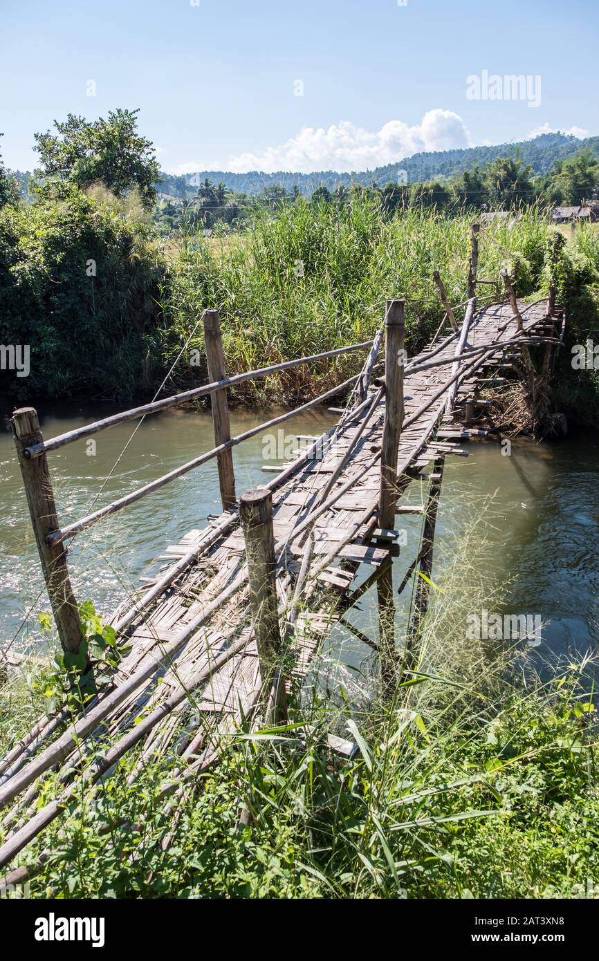 Old bamboo bridge is crossing the small river near the paddy field of ...