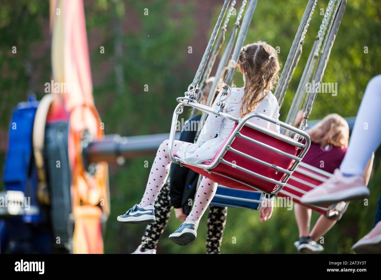 Little girl having fun on chain carousel. Happy summer memories ...