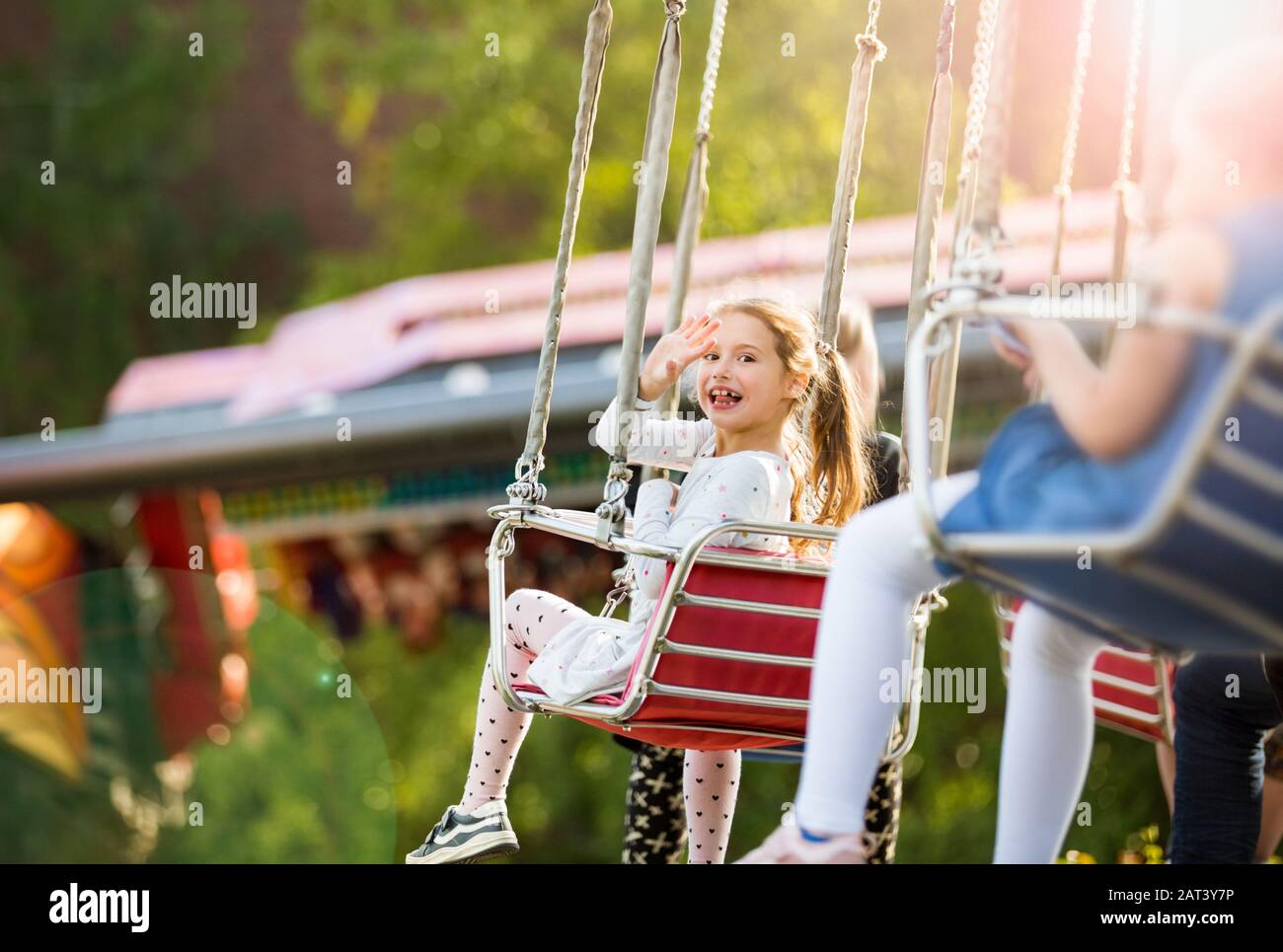 Little girl having fun on chain carousel. Happy summer memories ...