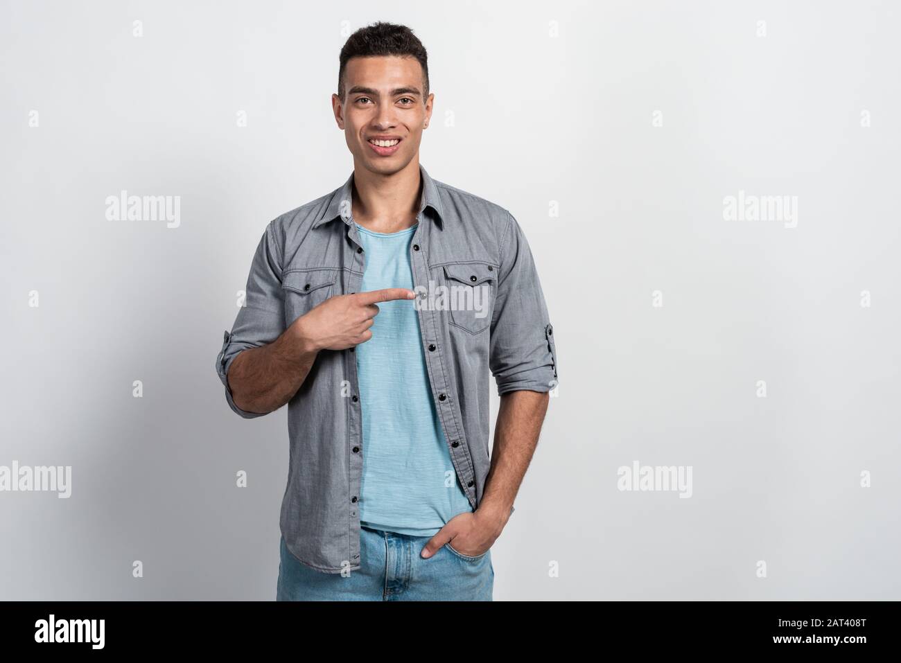 Half-length portrait a happy mulatto man standing against a white wall ...