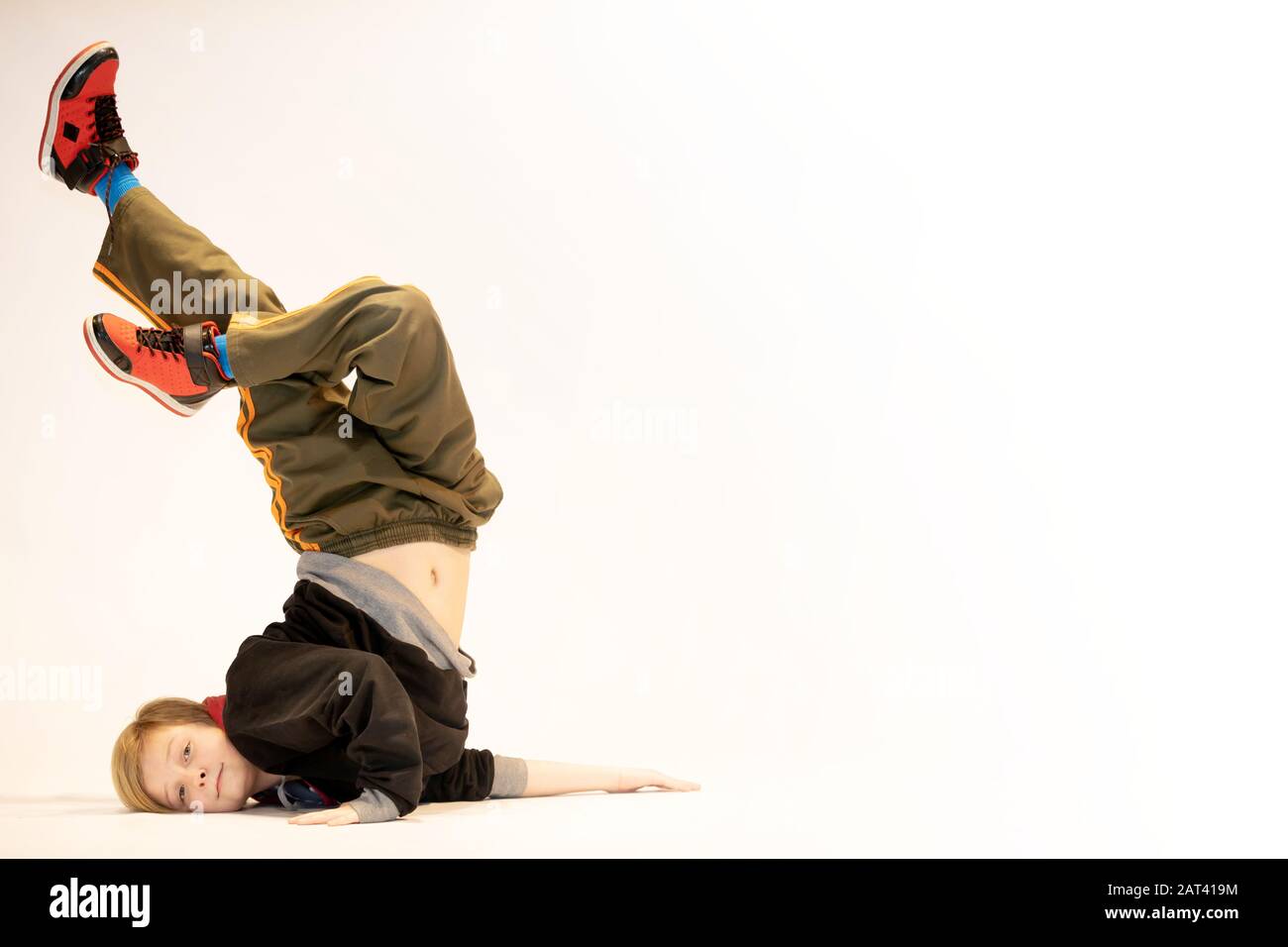 a little boy performs a unique breakdance figure while standing on his ...