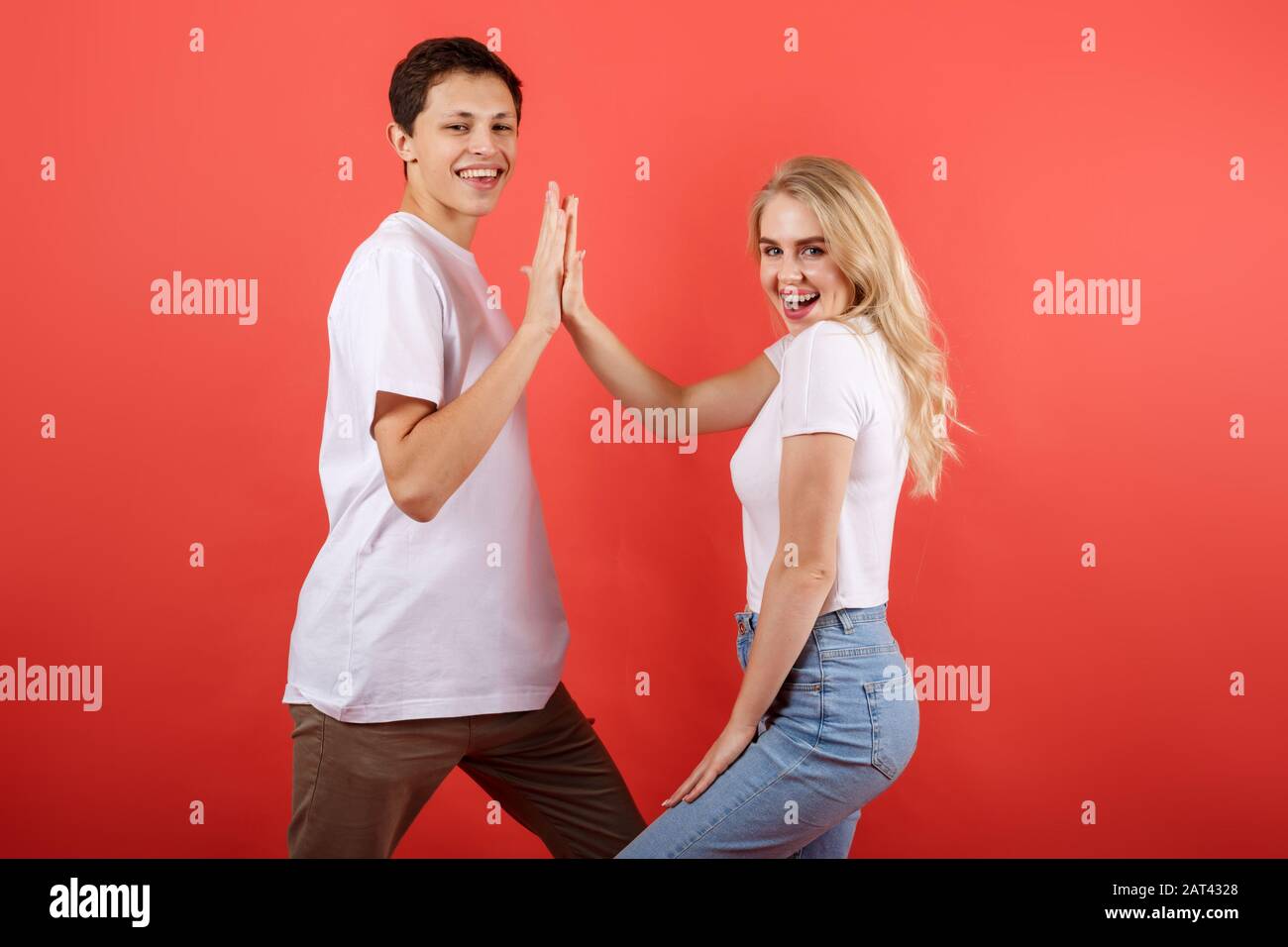 Happy teenage couple giving high five, over red background Stock Photo ...