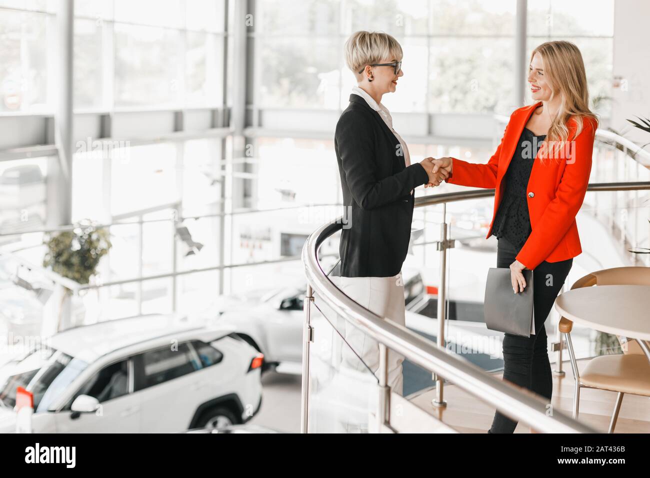 Two women - dealer and customer - make a deal and shake hands each ...