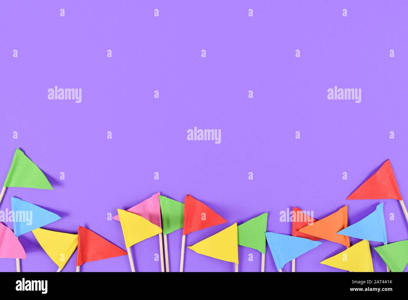 Colorful small paper flags at bottom on purple background with copy ...
