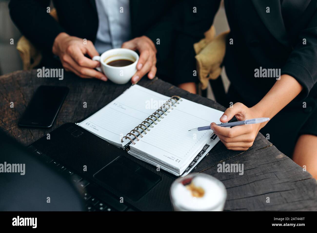 Closeup a paper planner. Female hand holding a pen and point to sheet ...