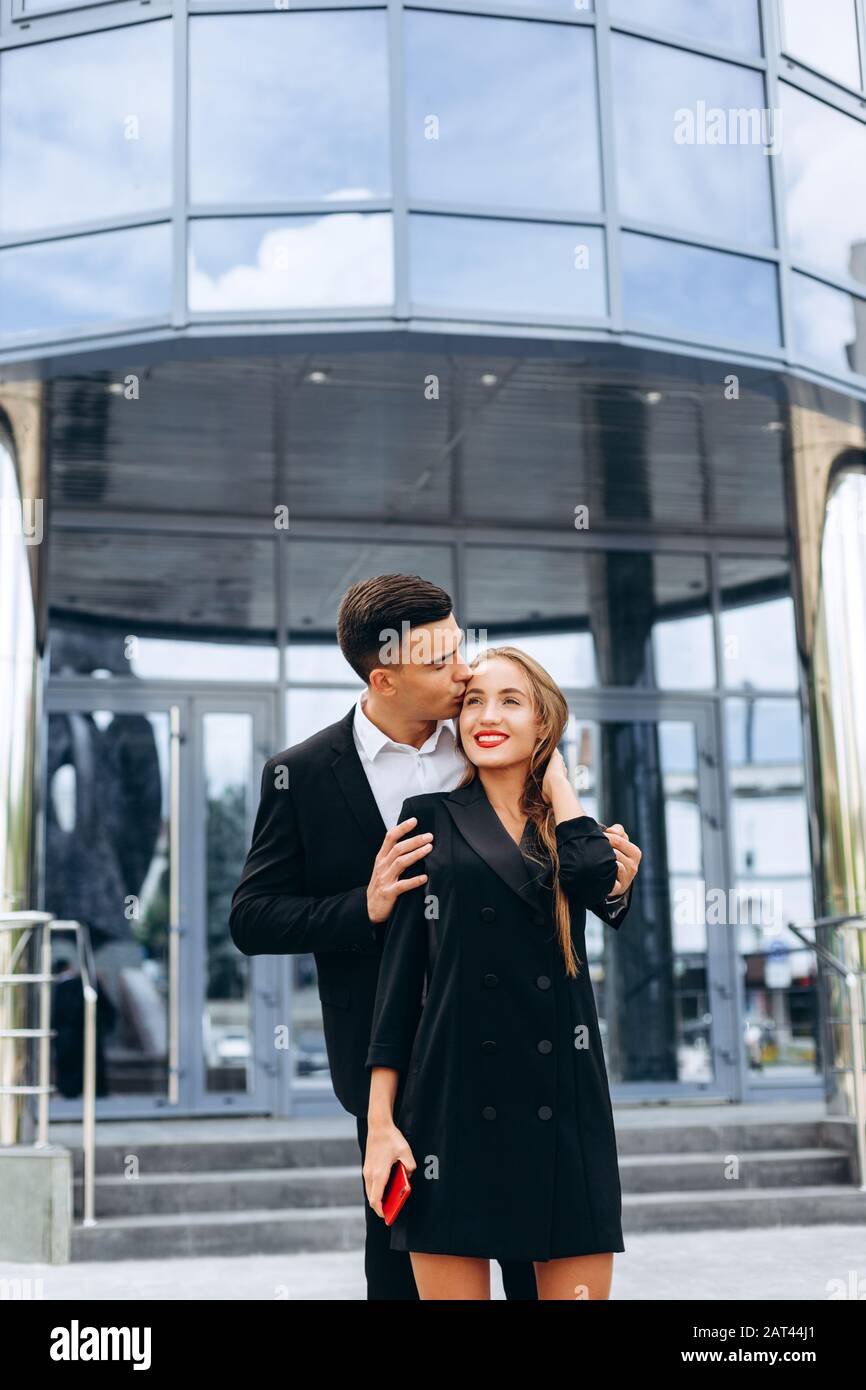 Man hugging a woman. Romantic couple standing against a office building ...