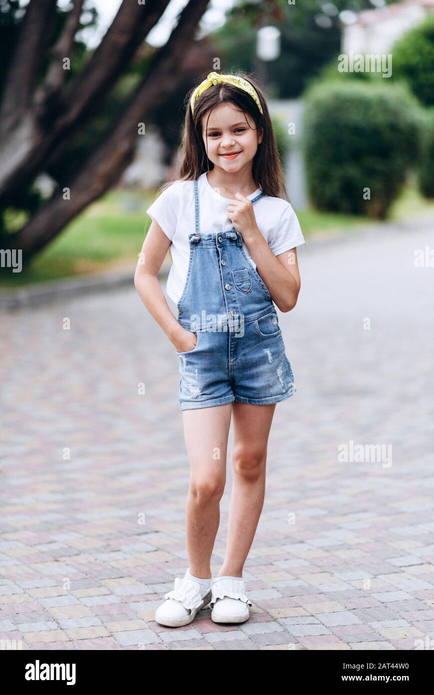 Full lenght portrait of happy little dirl standing and posing outdoor ...