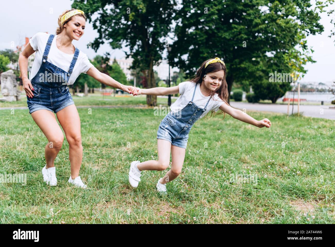 Happy little dirl holding her mom hand and running outdoor.- Image ...