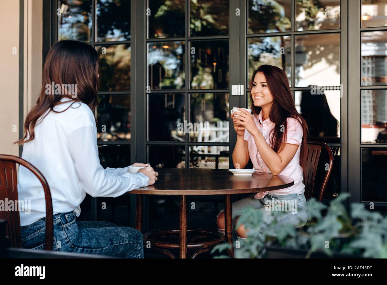 Pretty cute brunette talking to each other while sitting at the table ...