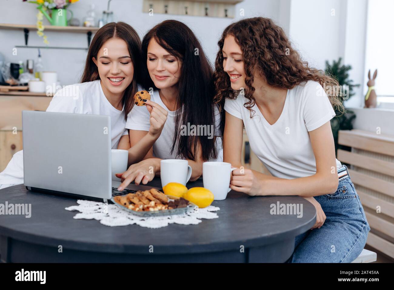 Happy family drinking tea at the table, eating cookies and looking at ...