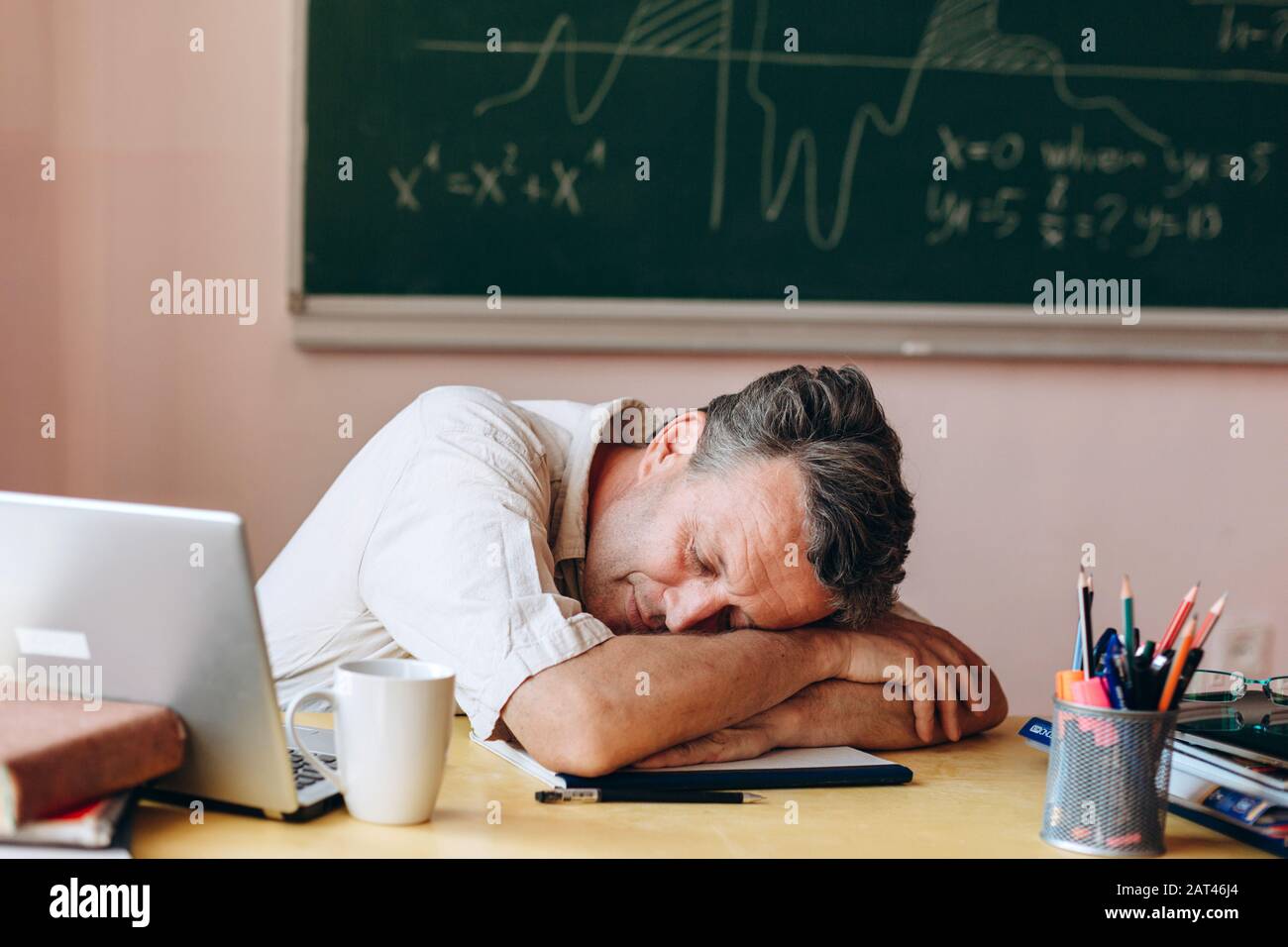 Teacher sleeping in the classroom, head down on the his hands Stock ...