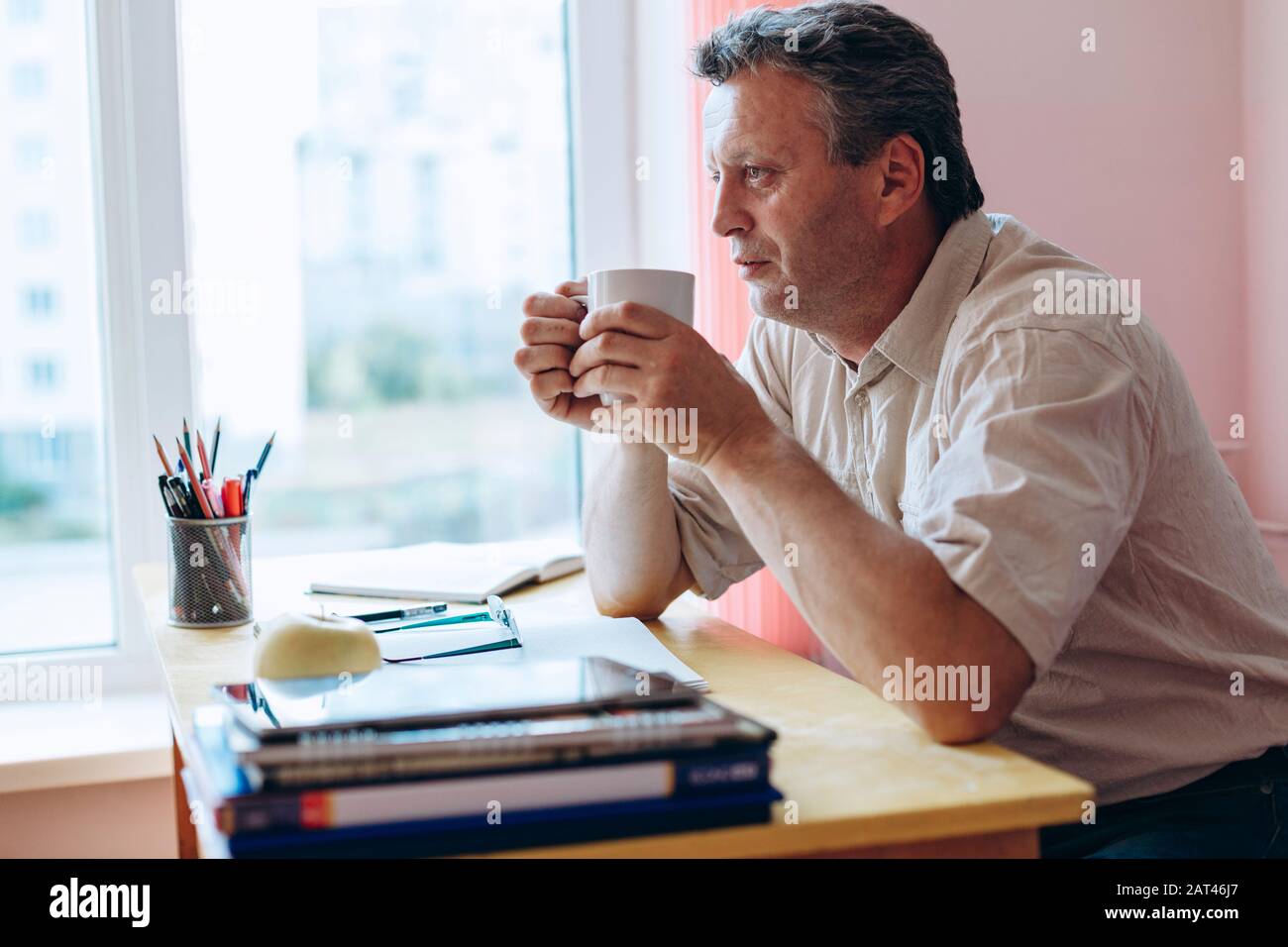 Teacher sitting at the table holding a cup in the classroom and have a ...
