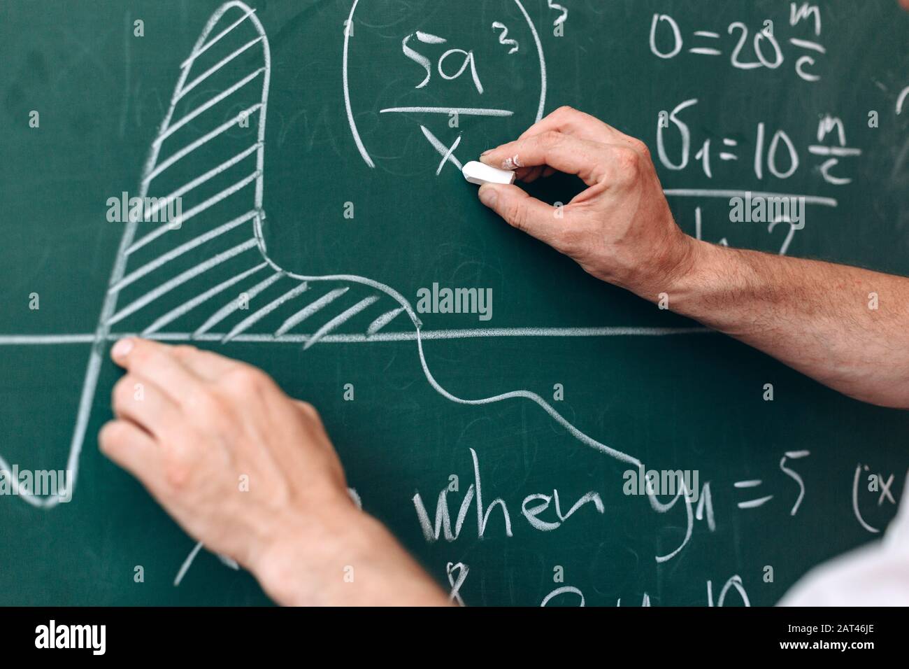 Closeup teacher's hands write on the blackboard an example.- Image ...