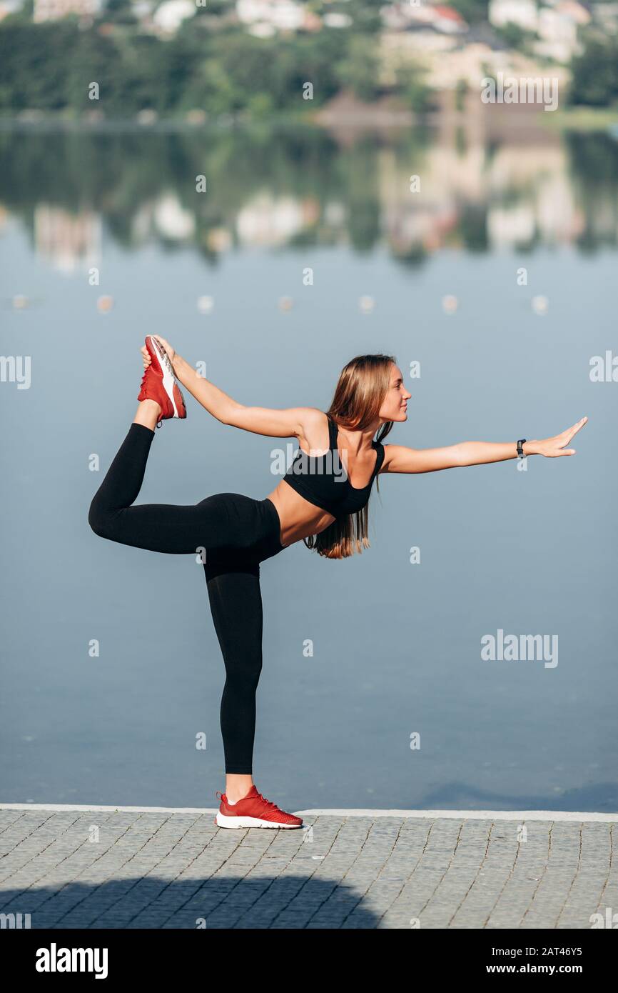 Happy girl doing yoga asana and holds by her hand her leg behind back ...